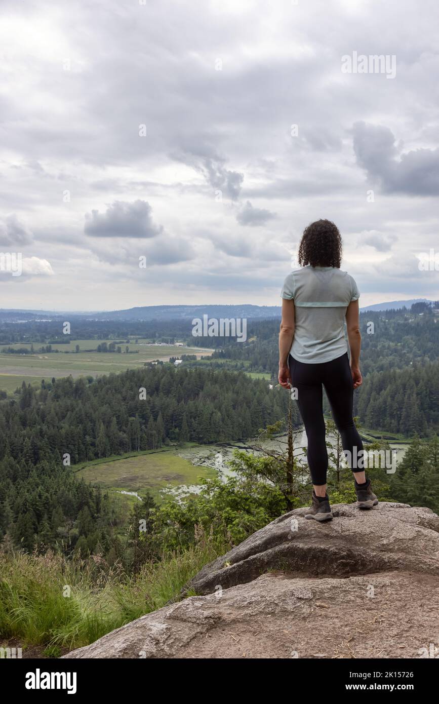 Adventurous Woman Standing on top of a rock overlooking the Canadian ...