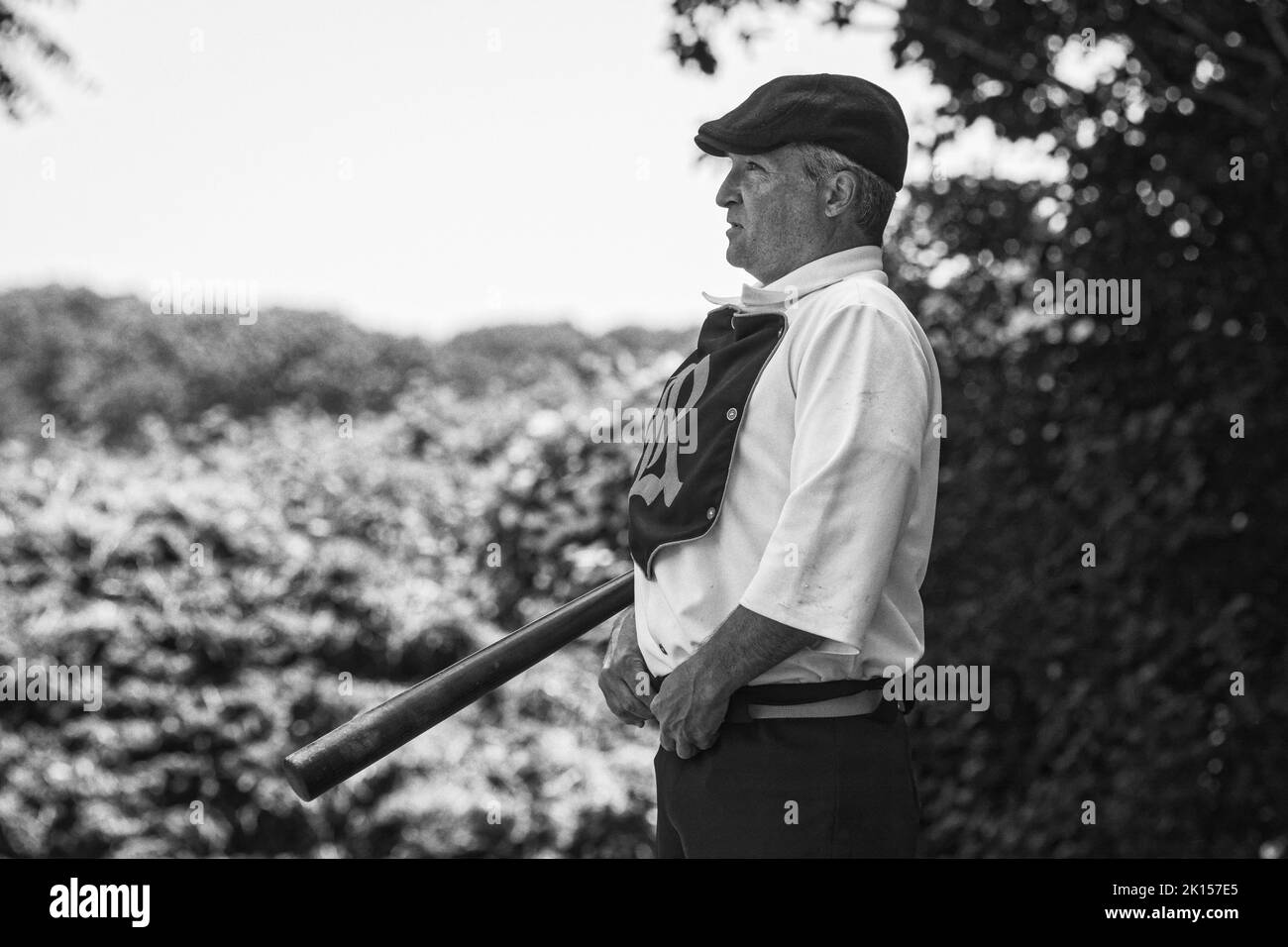 A baseball player stands in deep thought with a wood bat in hand ...