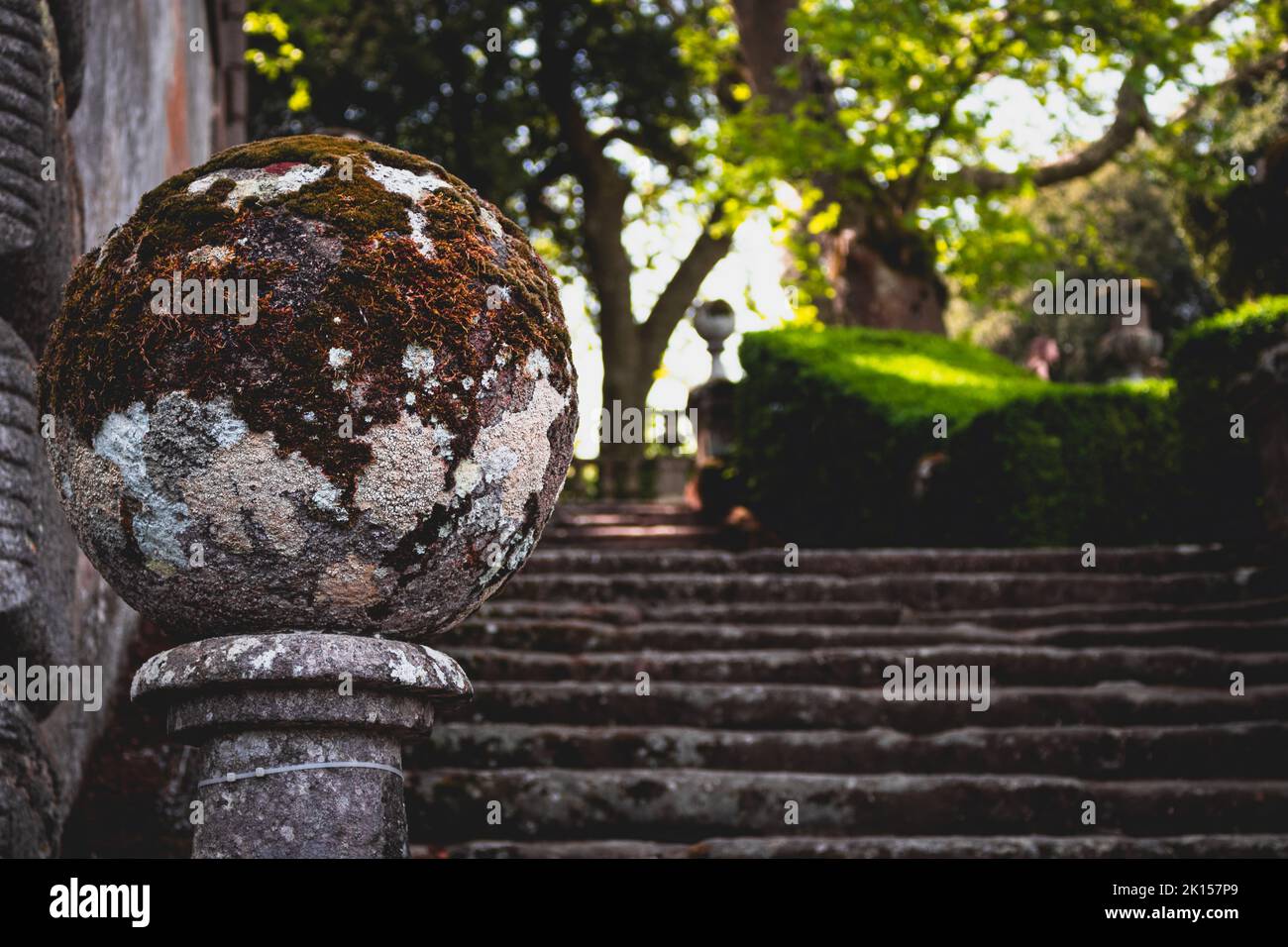 Mossy earth-looking spherical stone in a garden on top of a pillar ...