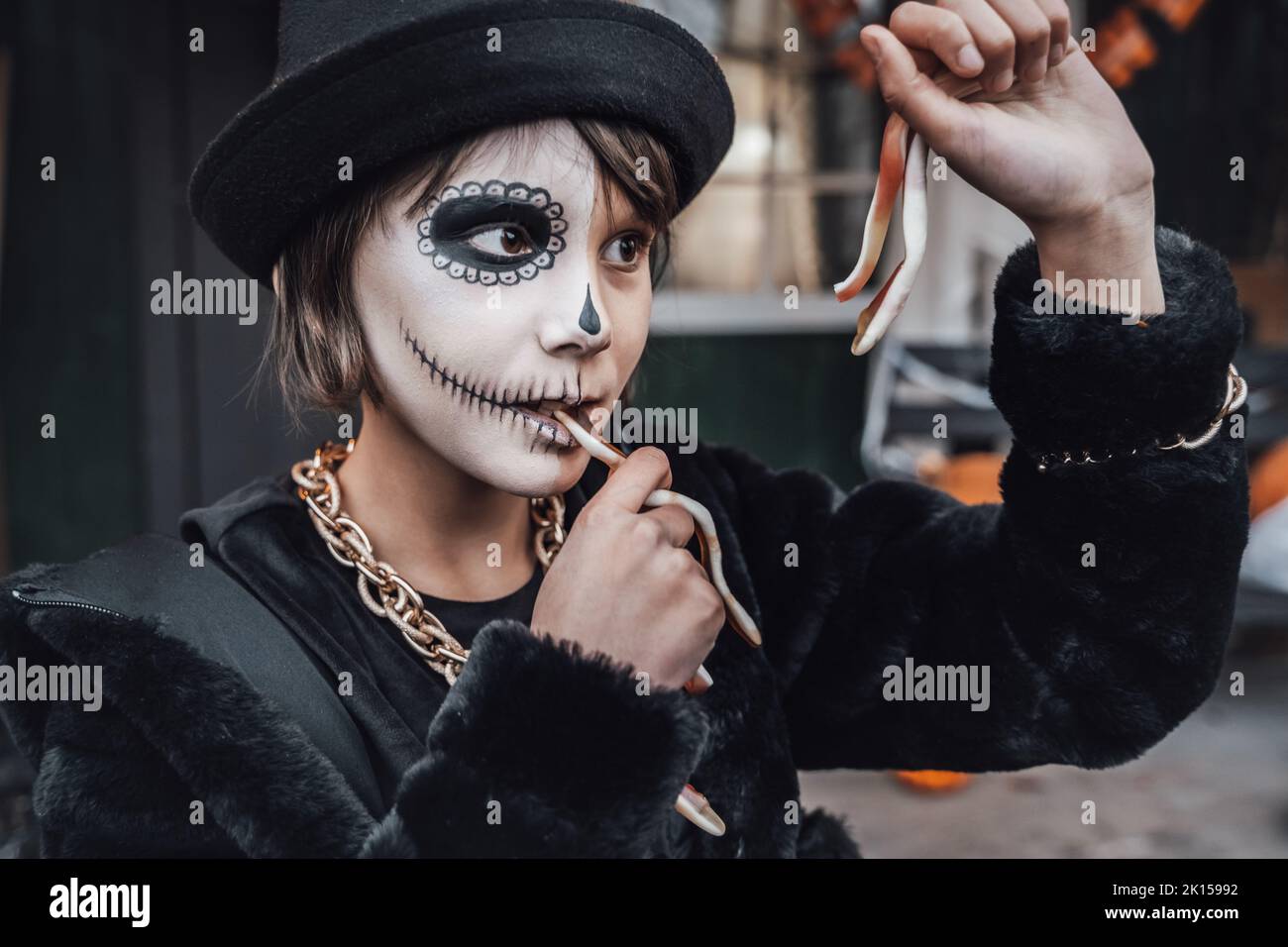 Beautiful scary little girl celebrating halloween, chewing gummy worm ...