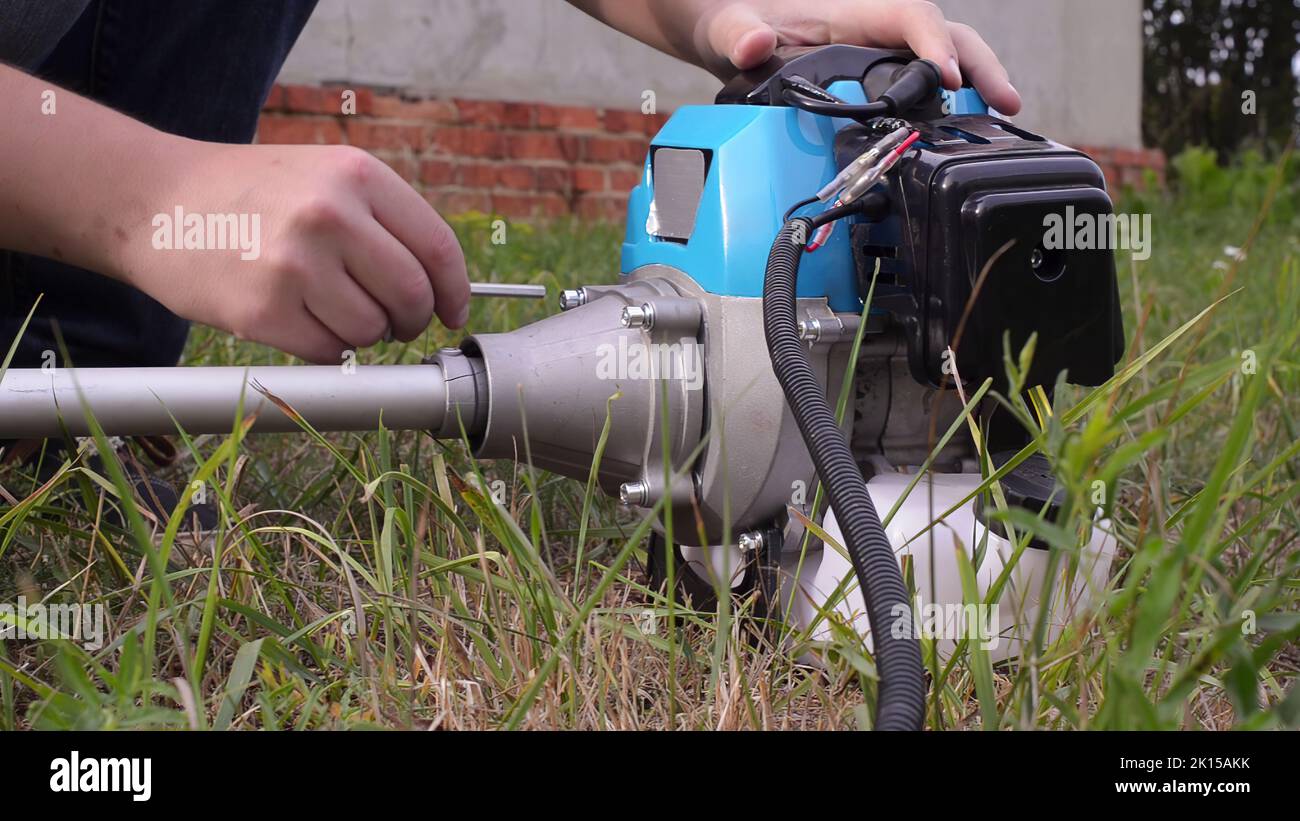 Young man assembling parts of the string trimmer Stock Photo - Alamy