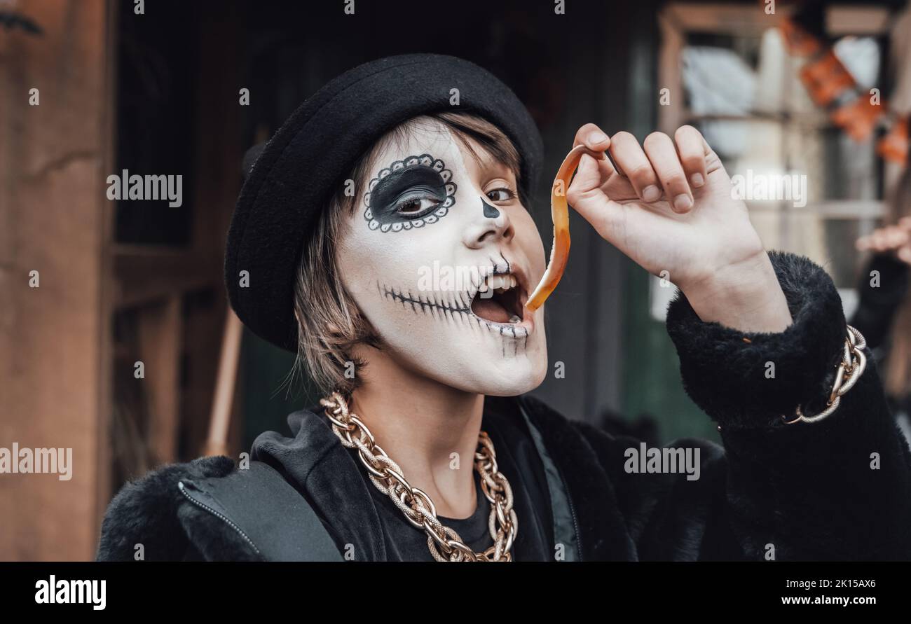 Beautiful scary little girl celebrating halloween, chewing gummy worm ...