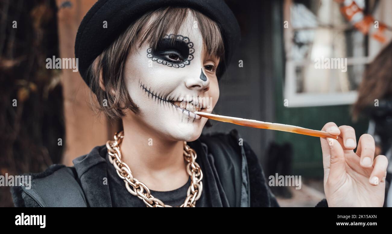 Beautiful scary little girl celebrating halloween, chewing gummy worm ...