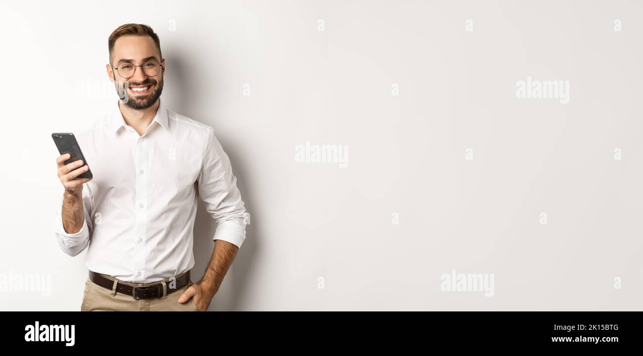 Handsome manager using smartphone and smiling pleased, sending text ...