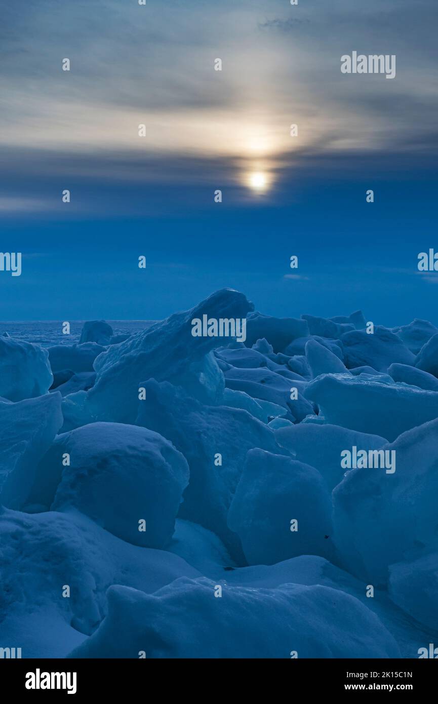Late afternoon winter light crisps the edges of the ice upturned in an ...