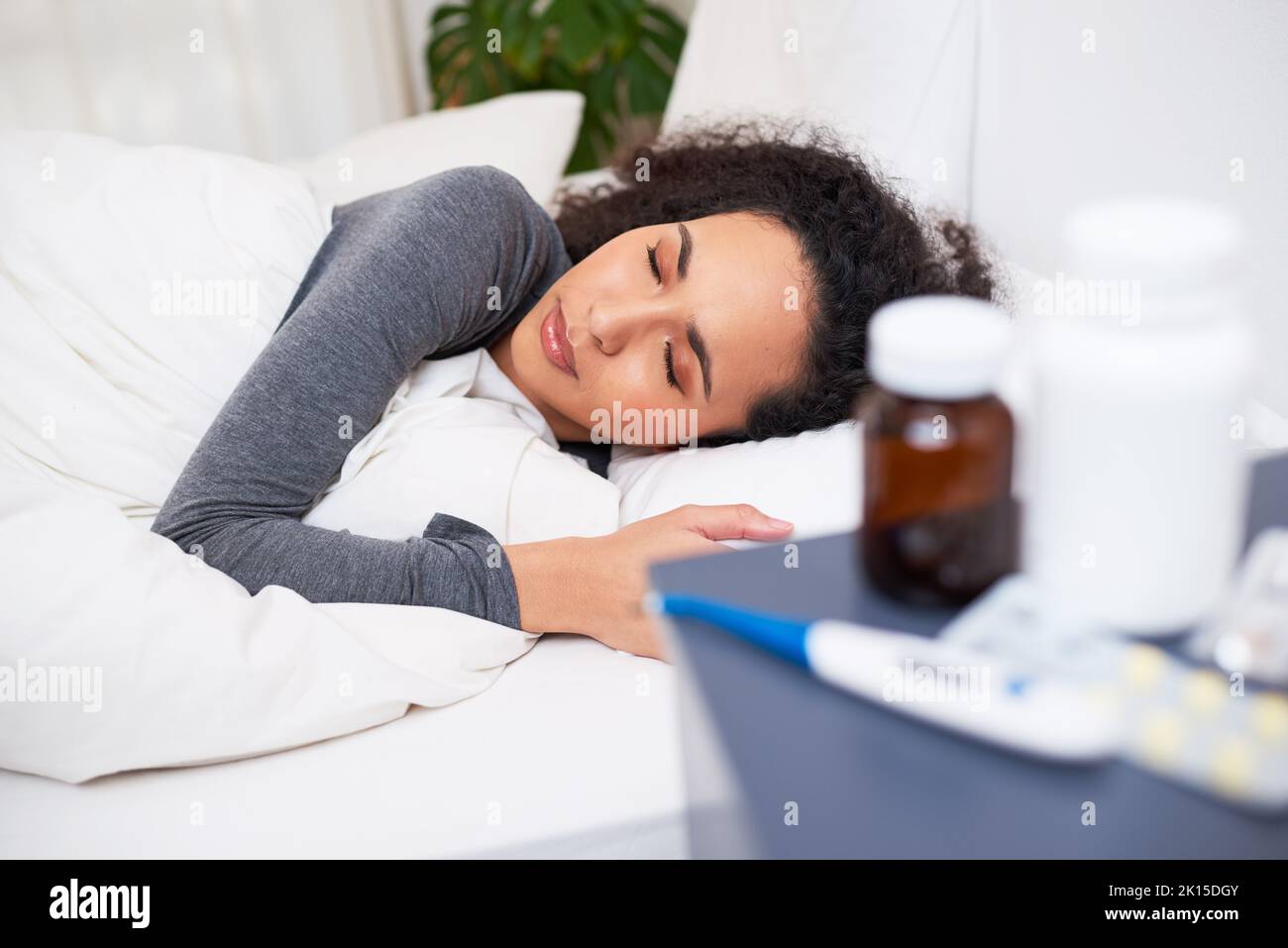 A young multi-ethnic woman sleeps in bed recovering from flu with ...