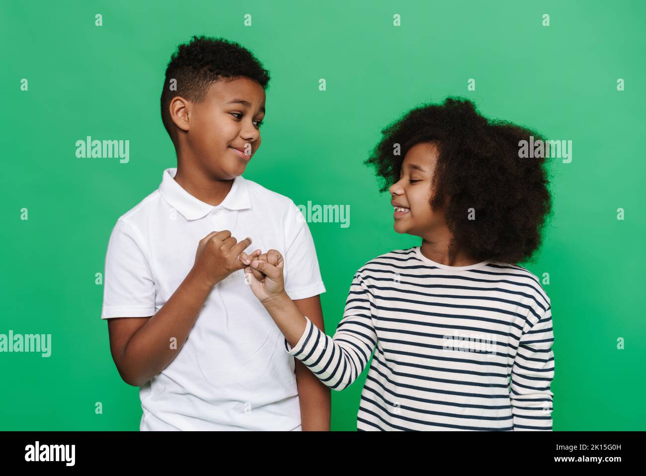 Black boy and girl hooking each other's little fingers in conciliation ...