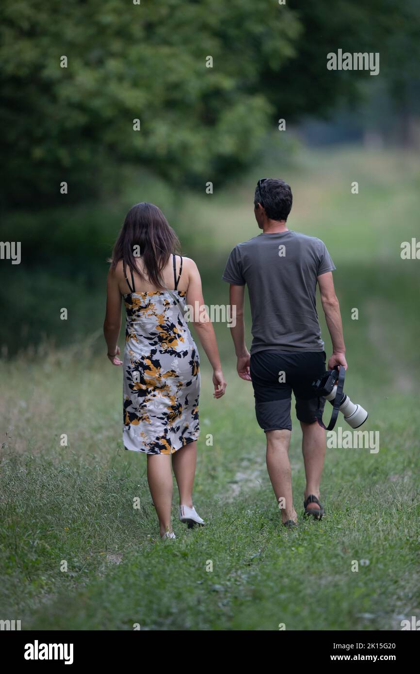 Mature couple waking in forest in summer time while man carrying ...