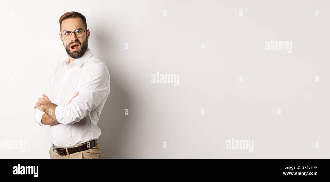 Confused manager looking at camera, standing shocked against white ...