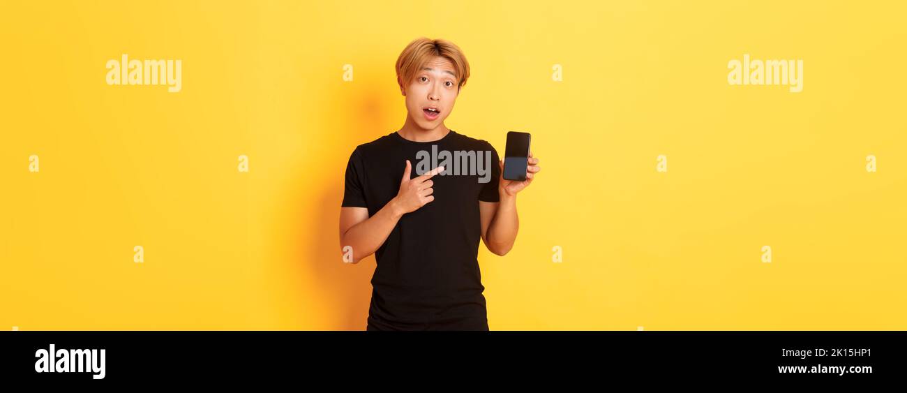 Portrait of handsome asian man showing something on smartphone screen ...