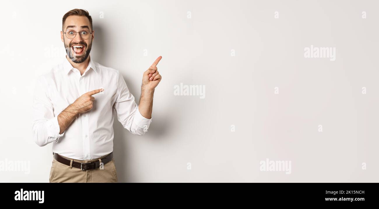 Excited handsome man pointing fingers at upper right corner, showing ...