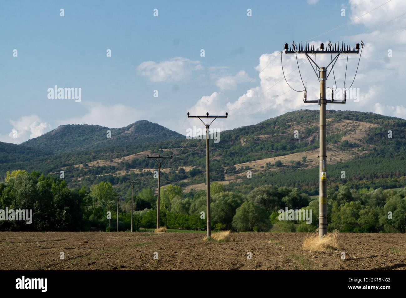 A beautiful scene of utility poles in the field with green hills in the ...