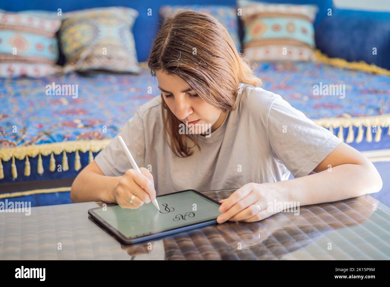 Calligrapher Young Woman writes phrase on digital tablet. Inscribing ...