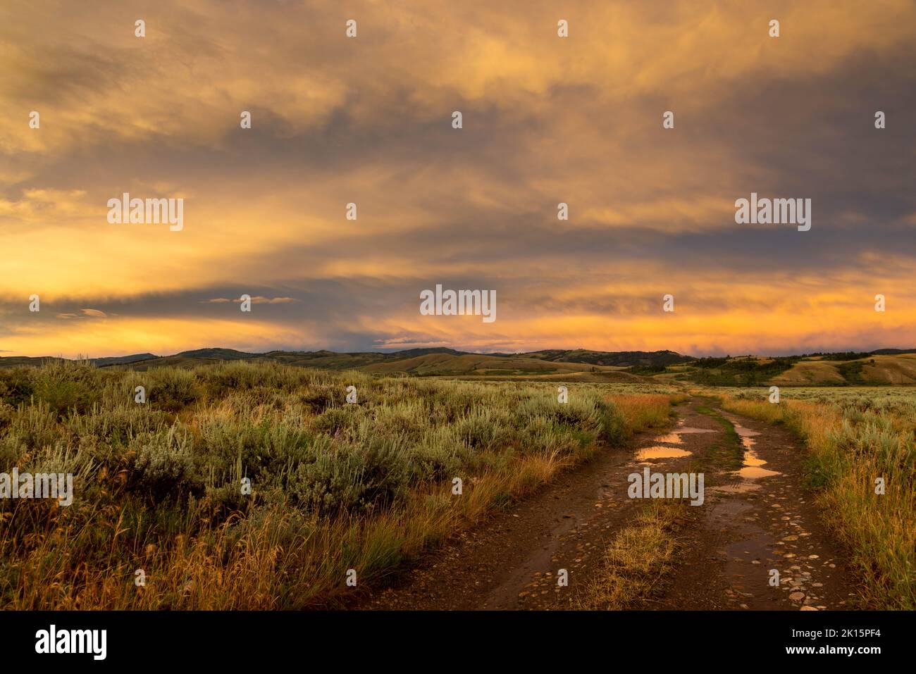 A dirt road passing through sagebrush on Antelope Flats below a stormy sunset. Grand Teton ...