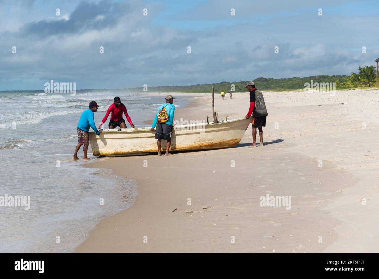 Fishermen are seen pushing a boat on the beach. Guaibim beach in the ...