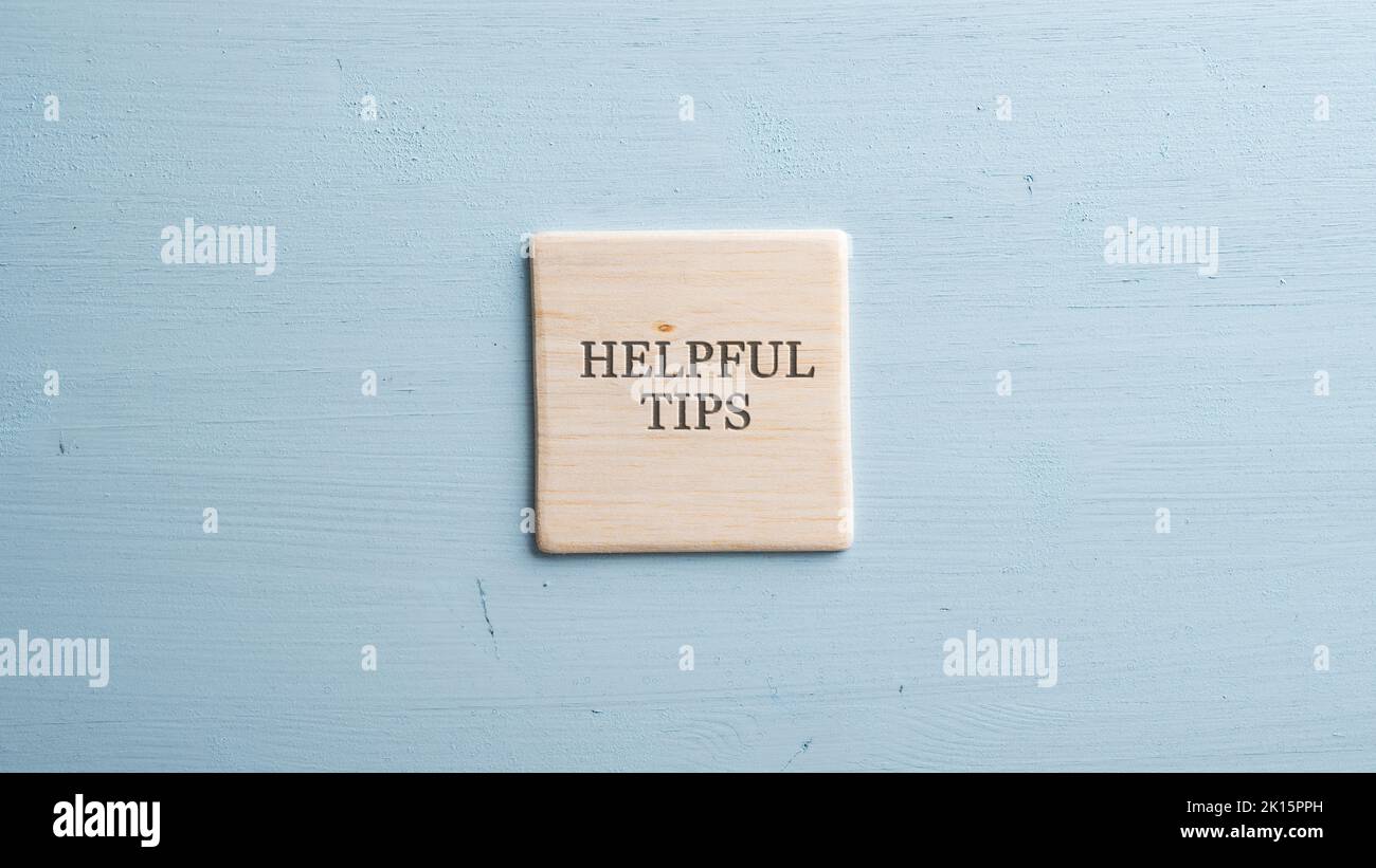 Helpful tips sign cut into wooden tile placed over pastel blue ...