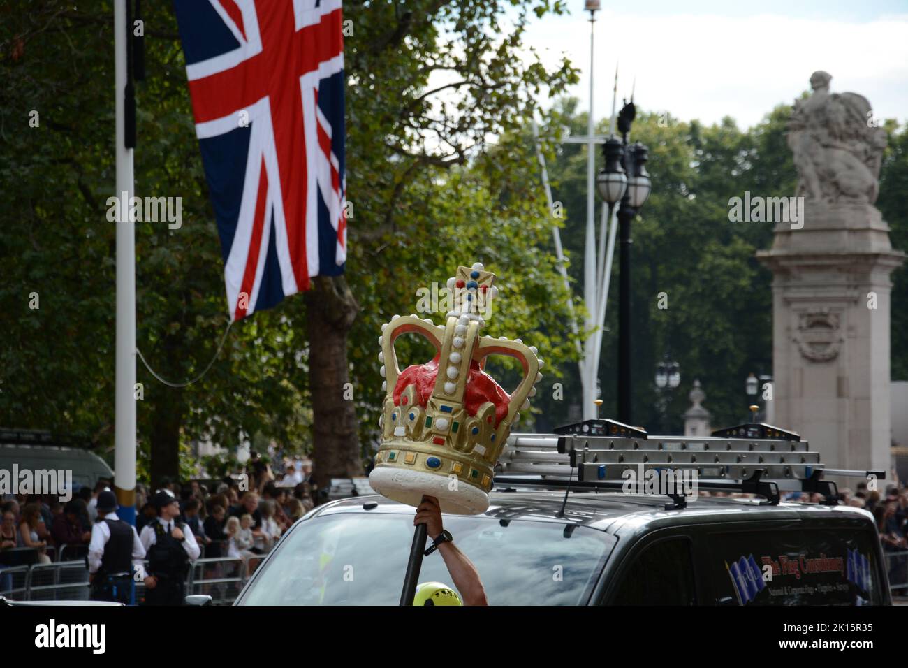 A worker carries a giant crown he will soon attach to a pole in the ...