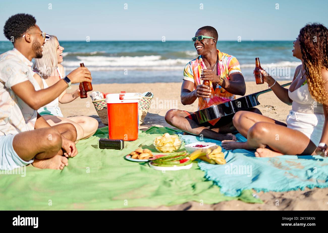 Multiracial men and women in casual clothes drinking beer and eating ...