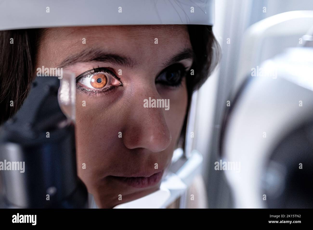 Closeup female patient with eye illuminated with light waiting for tonometer to finish measure ...