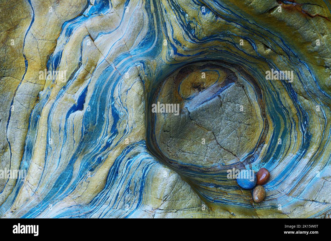 Bunch of small colorful smooth pebbles placed inside round hole in ...