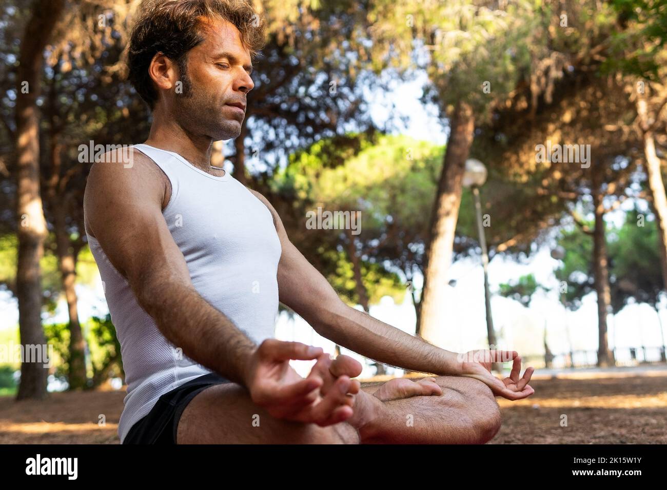From below side view of barefoot focused male sitting in Lotus pose ...