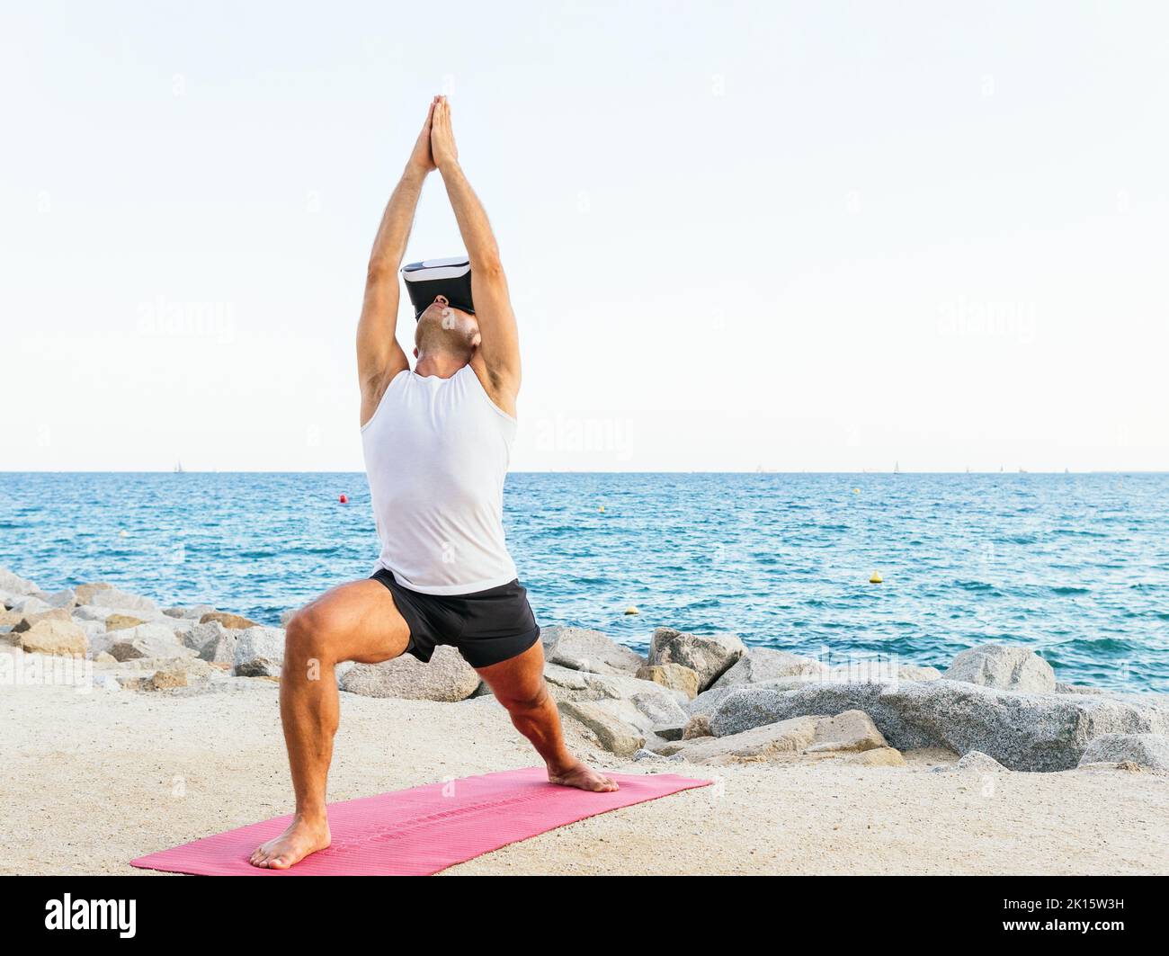 Full body man in activewear and VR headset raising arm and bending back ...