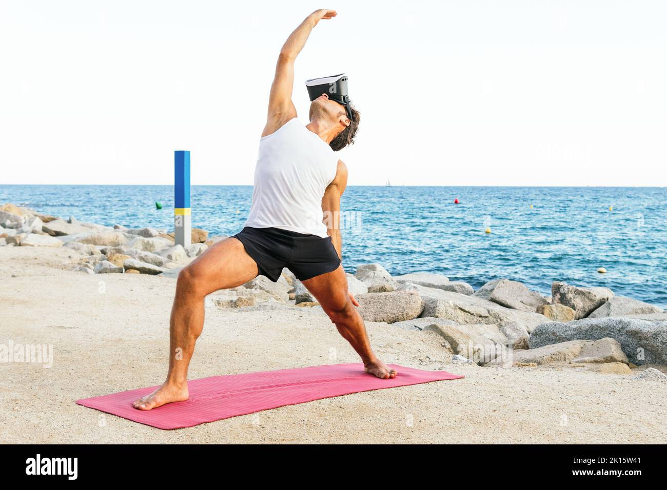 Full body man in activewear and VR headset raising arm and bending back ...