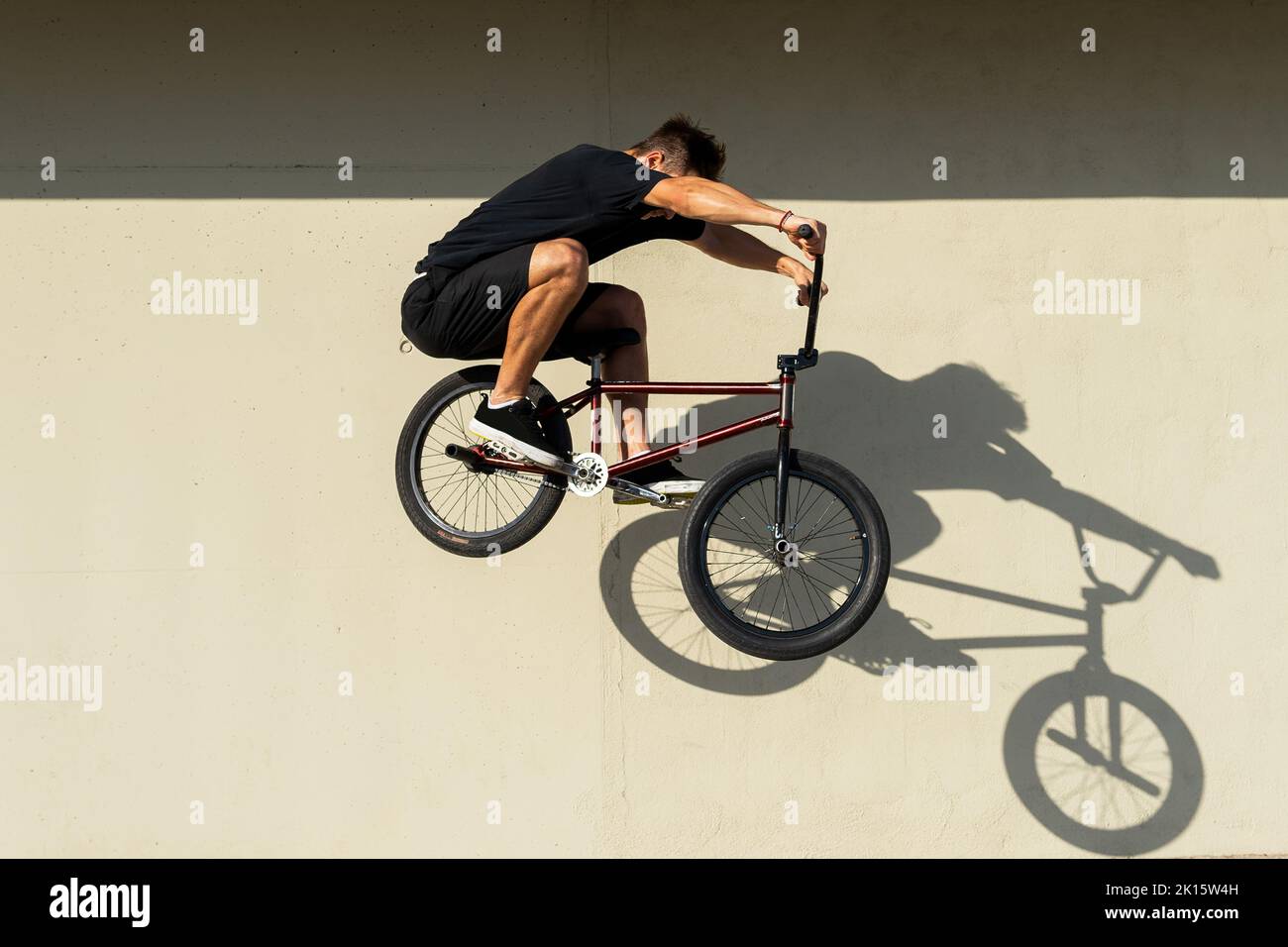 Full body side view male in casual clothes jumping on BMX bicycle ...