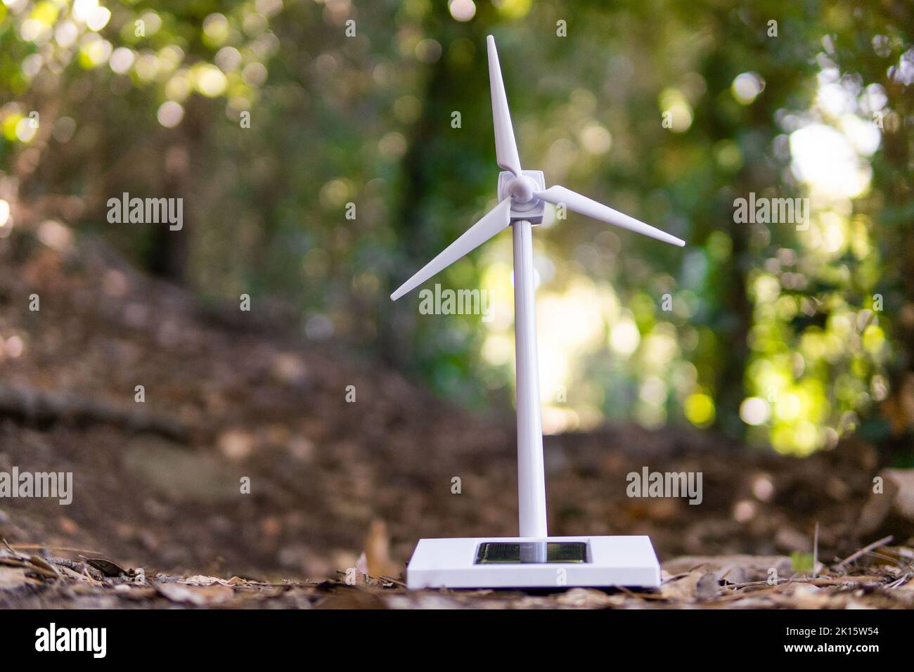 Portable white solar powered windmill toy placed on ground in lush ...