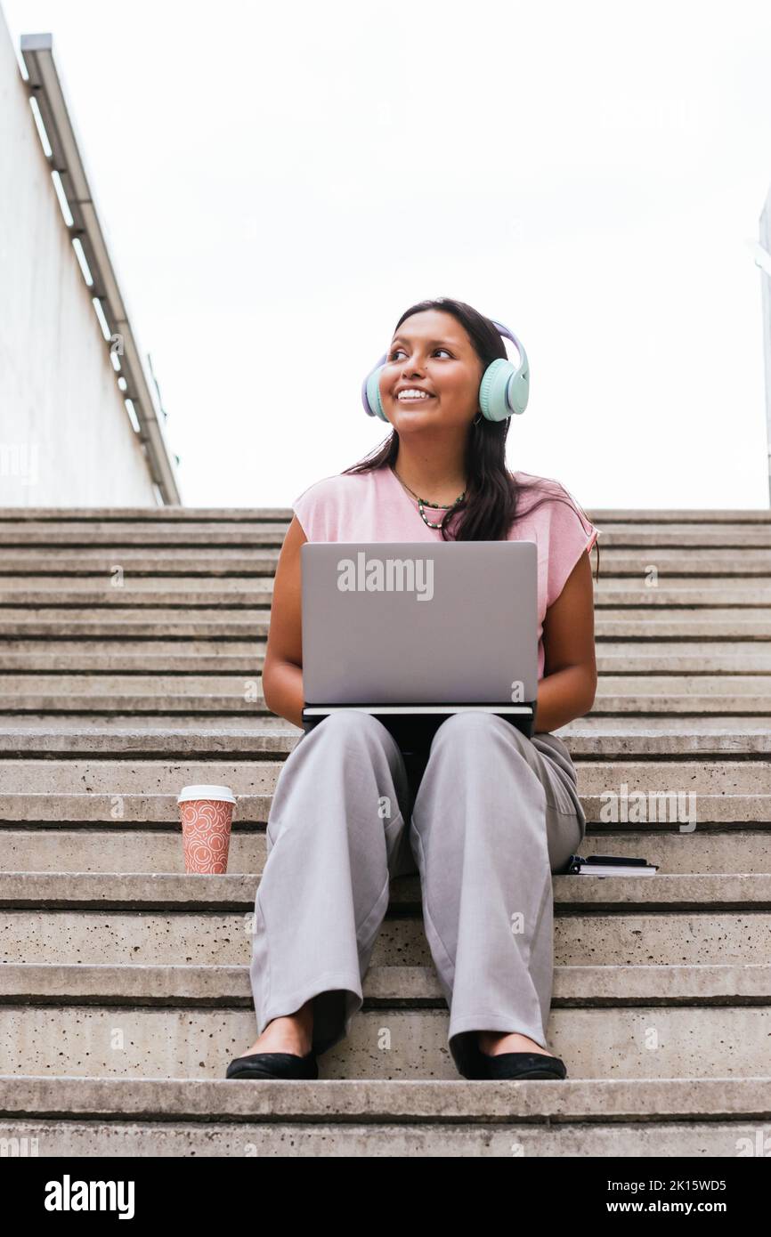 Positive young ethnic self employed woman with long dark hair in casual ...