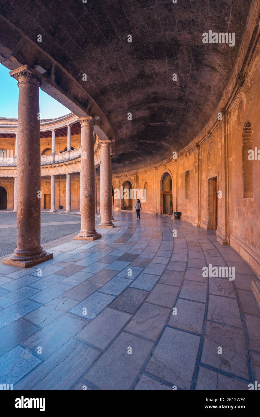 Tourist walking near pillars in patio of Palace of Charles V during visiting Alhambra fortress ...