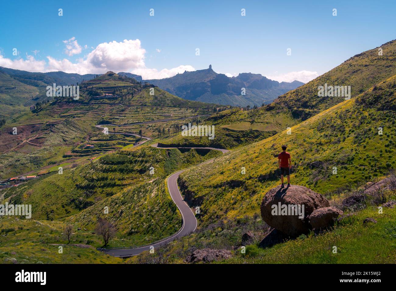 Back view of male adventurer standing on rock in highlands and enjoying ...