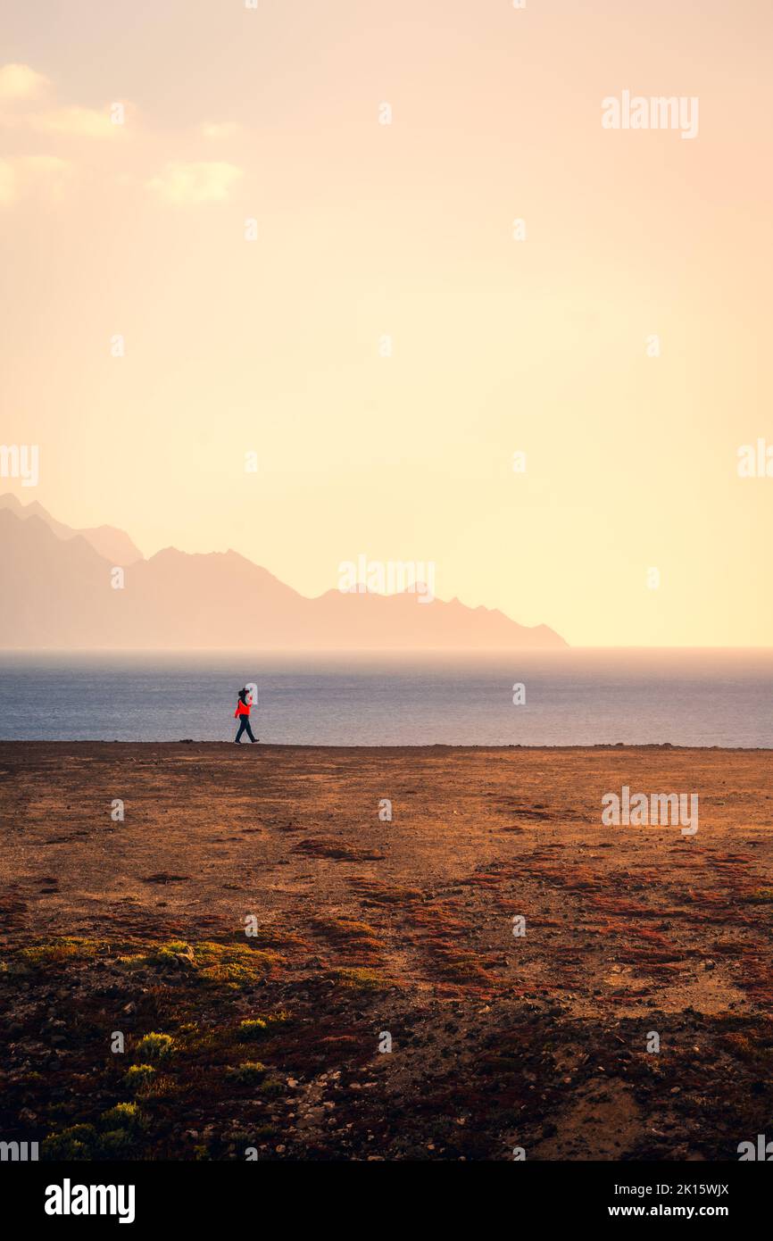 Remote side view of unrecognizable female explorer walking along rocky ...