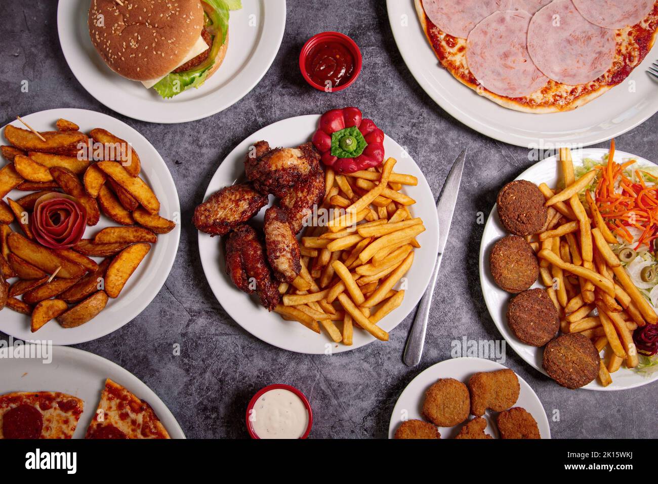 Top view of plates with assorted junk food dishes placed on gray table ...