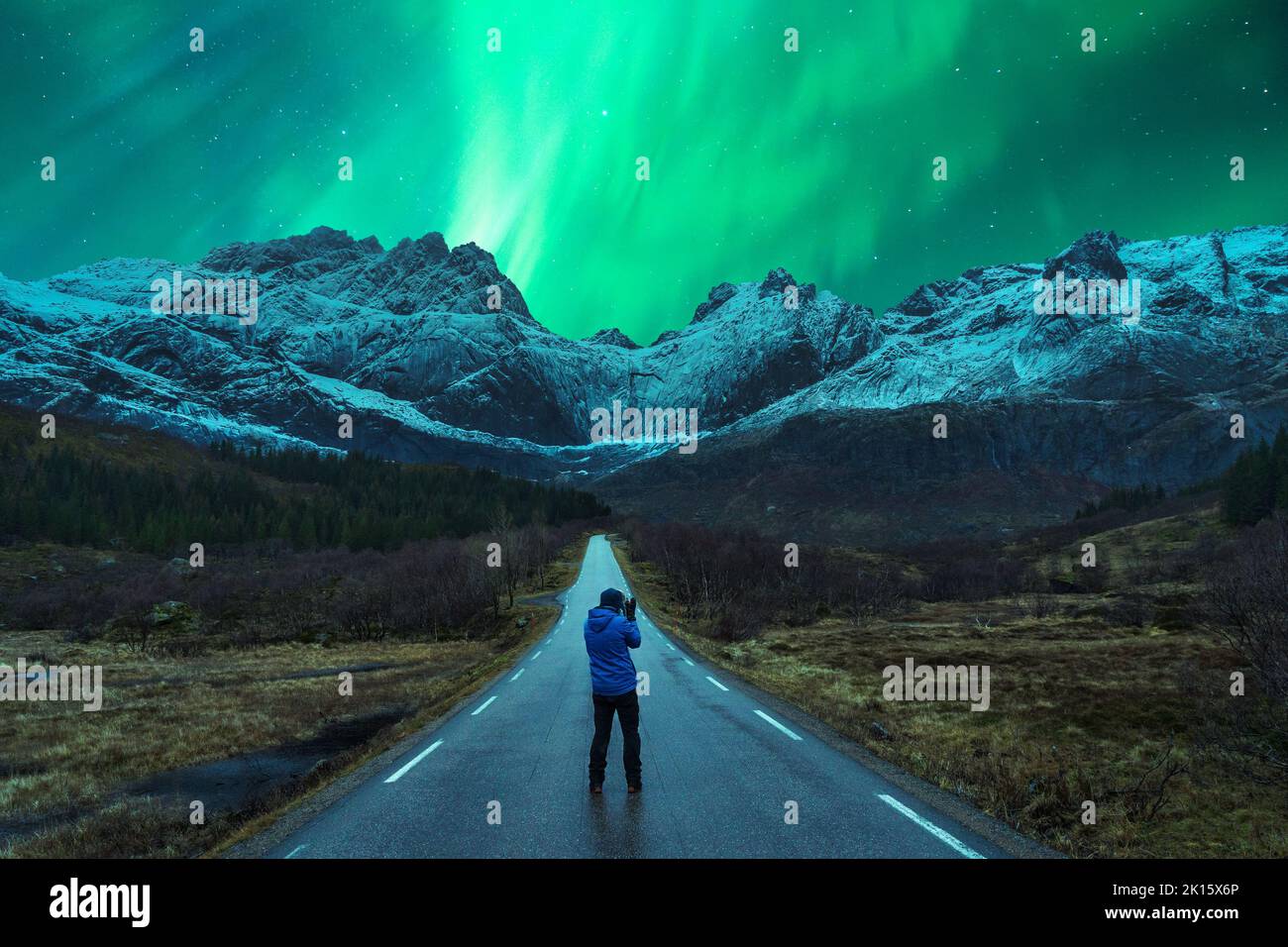 Distant view of explorer standing on asphalt road in snowy mountains ...