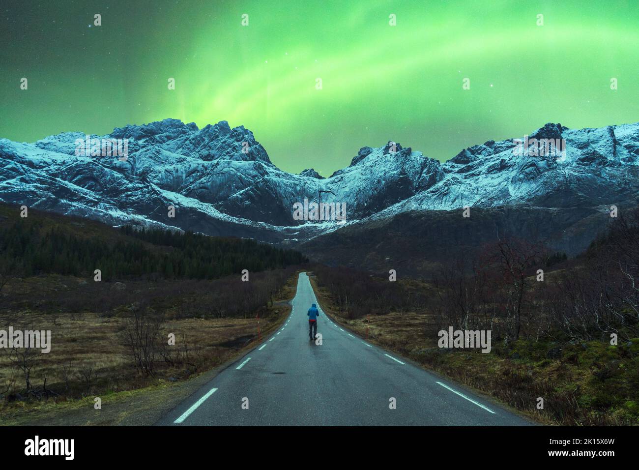 Distant view of explorer standing on asphalt road in snowy mountains ...
