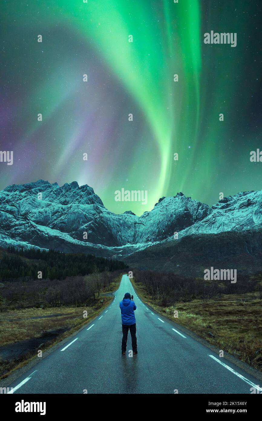 Distant view of explorer standing on asphalt road in snowy mountains ...
