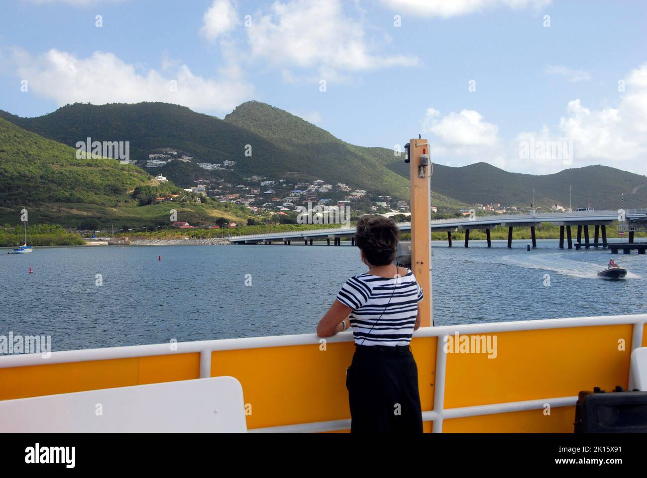 Woman on small local cruise boat looking at Simpson Bay causeway and ...