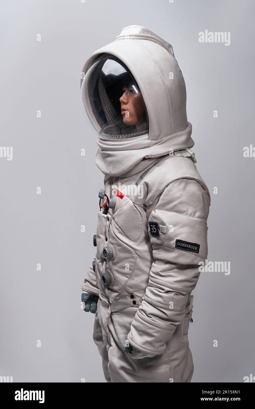 Asian woman in astronaut costume and helmet looking away during space ...