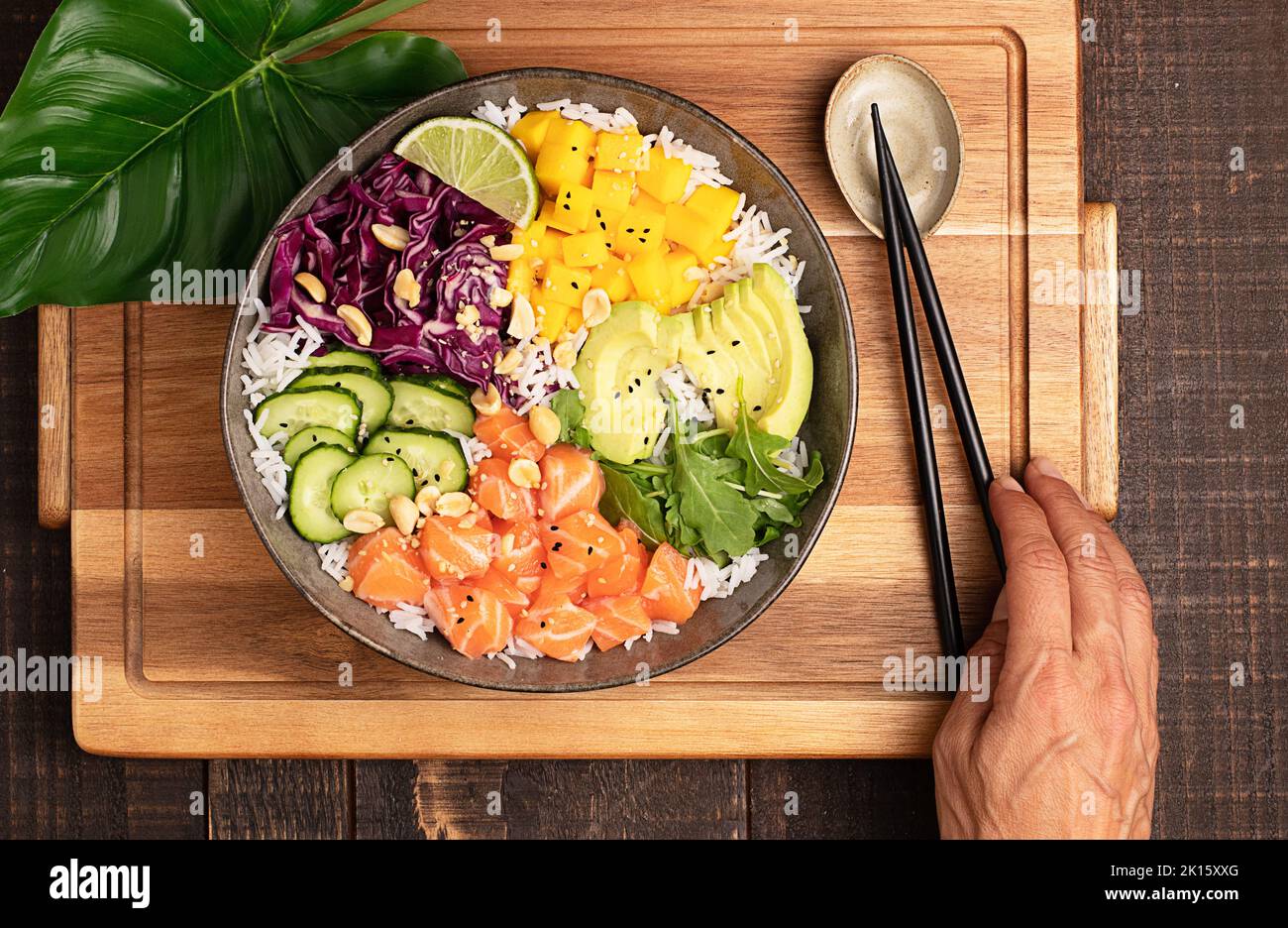 Top view of cropped unrecognizable person eating colorful poke bowl ...