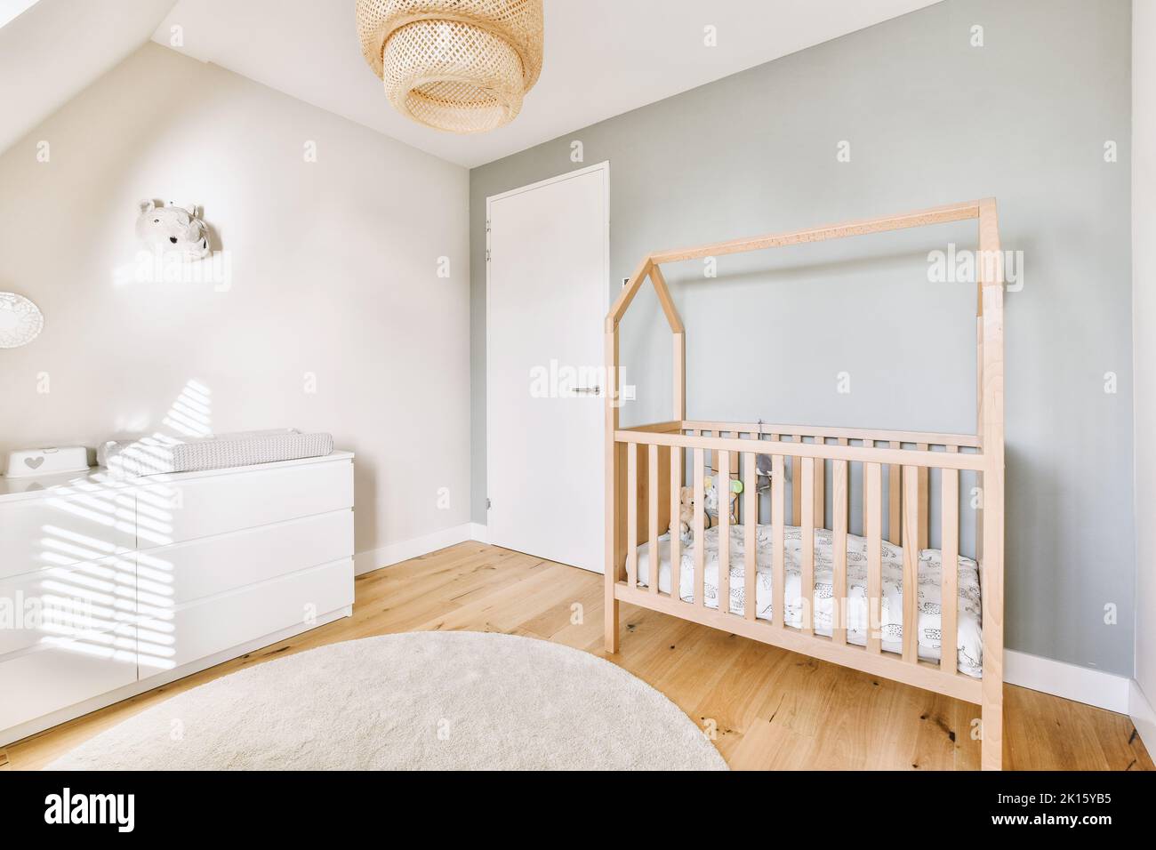 Wooden cradle with canopy against blue wall in contemporary nursery ...