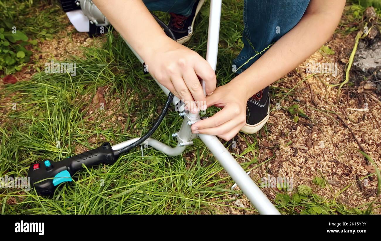 A man assembles the handle of string trimmer in the garden Stock Photo ...