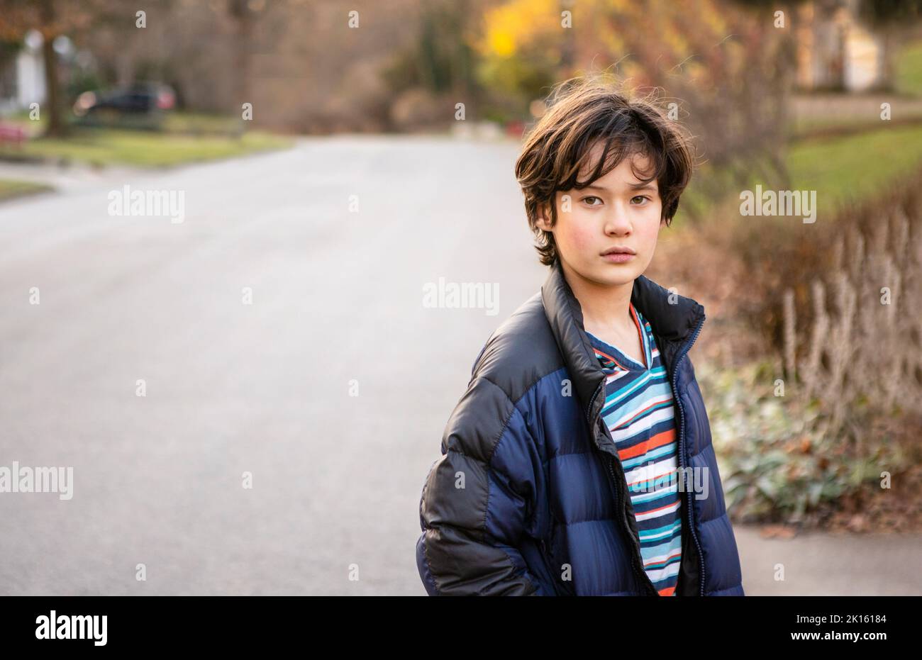 A beautiful tween boy with direct gaze walk on street in autumn Stock ...