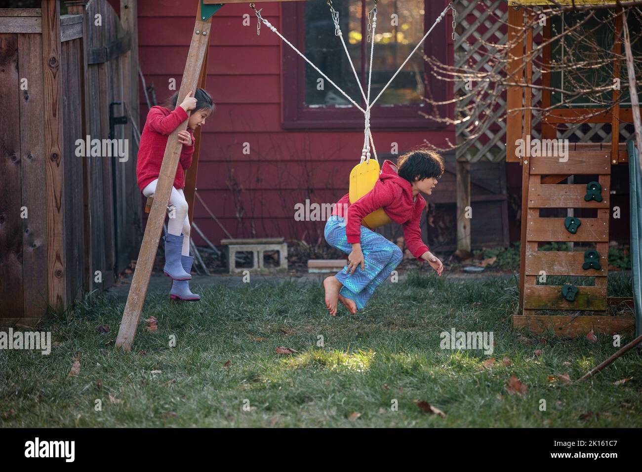 two children play on backyard playset together in springtime Stock ...