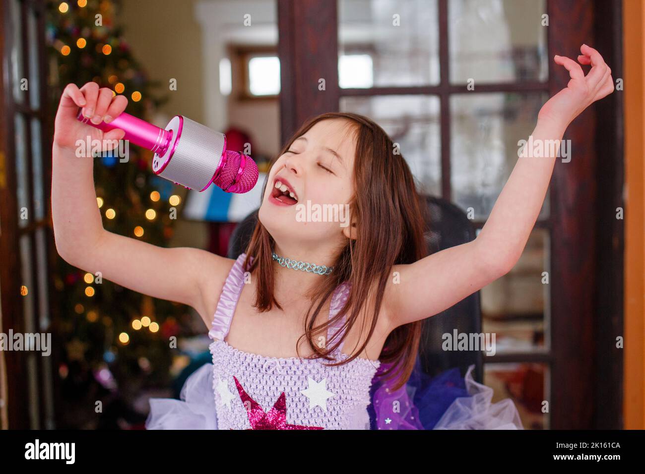 A girl with a pink microphone and tutu joyfully sings alone Stock Photo ...