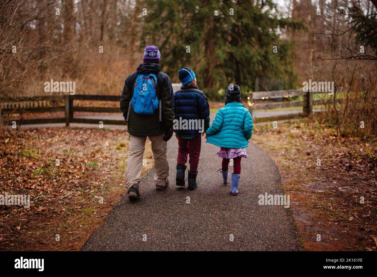 A father and children take a walk down wooded path at dusk Stock Photo ...