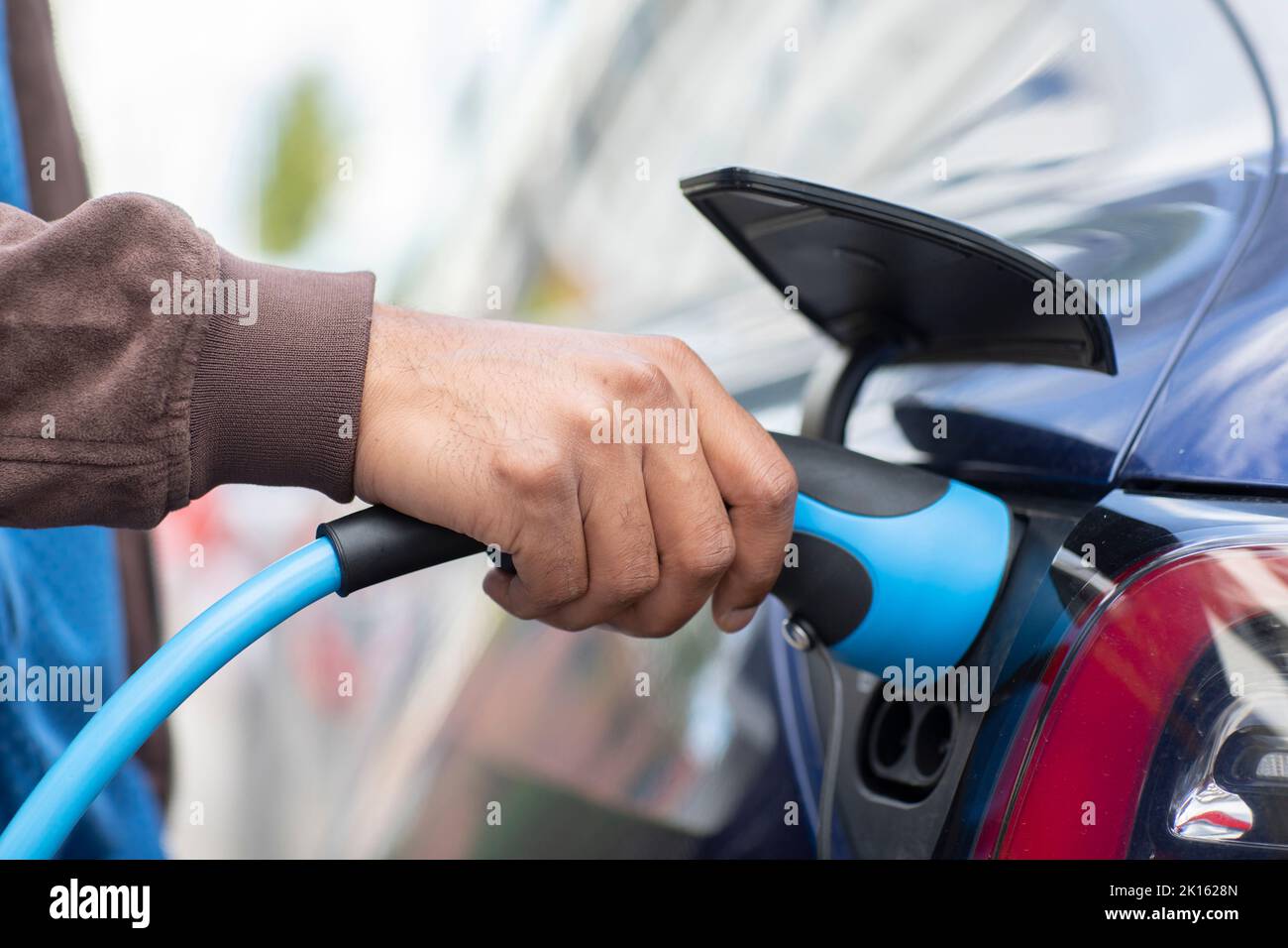 a hand holding charging cable at an e charging station Stock Photo - Alamy