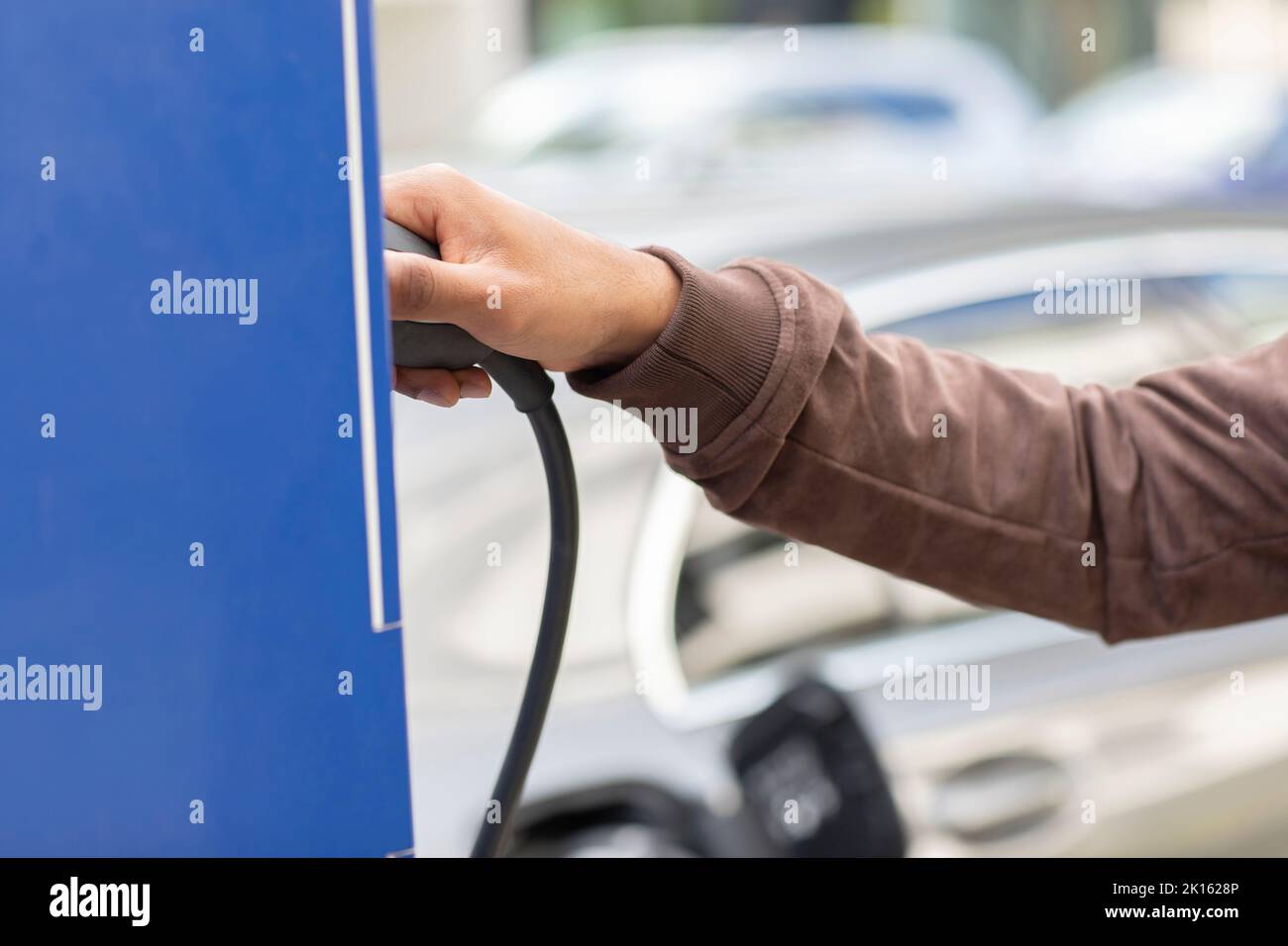 a hand holding charging cable at an e charging station Stock Photo - Alamy