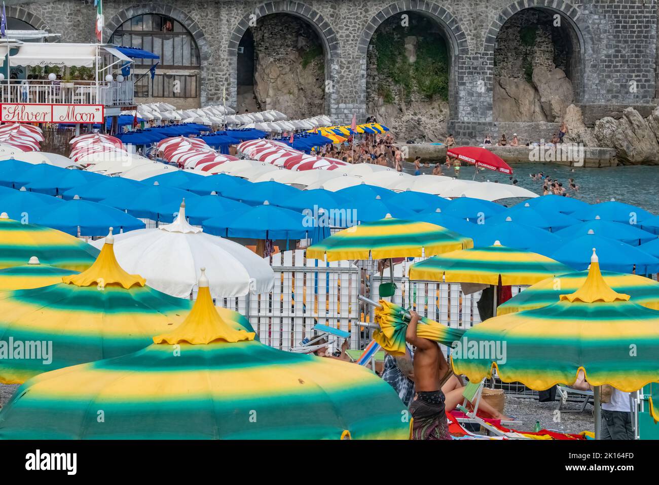 Amalfi Coast beach umbreallas a man carries a colorful European beach ...
