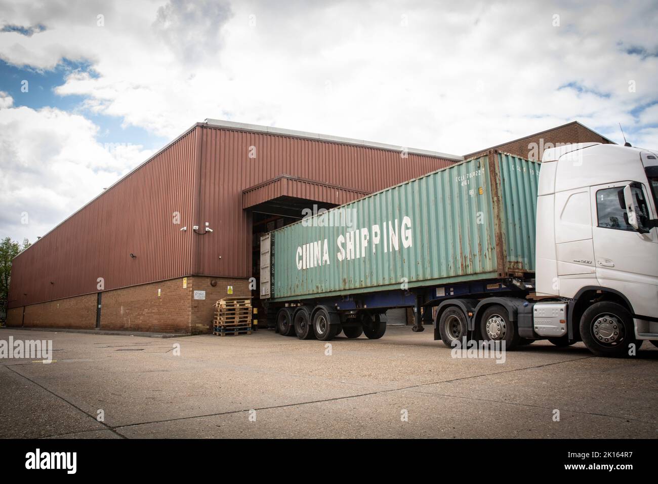 truck delivering cargo and goods in shipping containers, to a warehouse ...